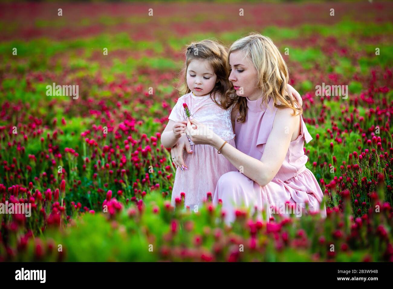 Beautiful smiling child girl with young mother in family look in field ...