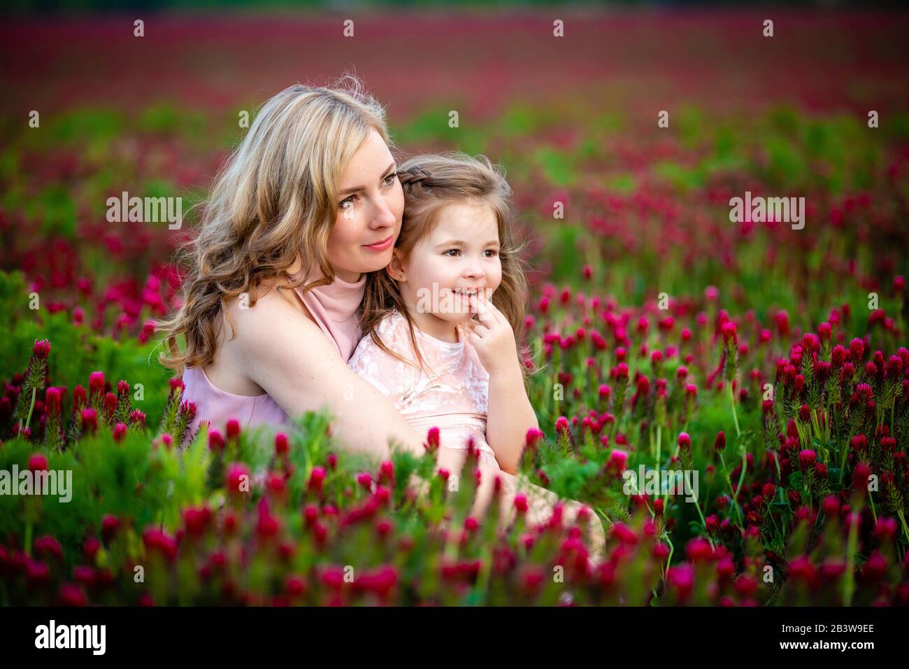 Beautiful smiling child girl with young mother in family look in field ...