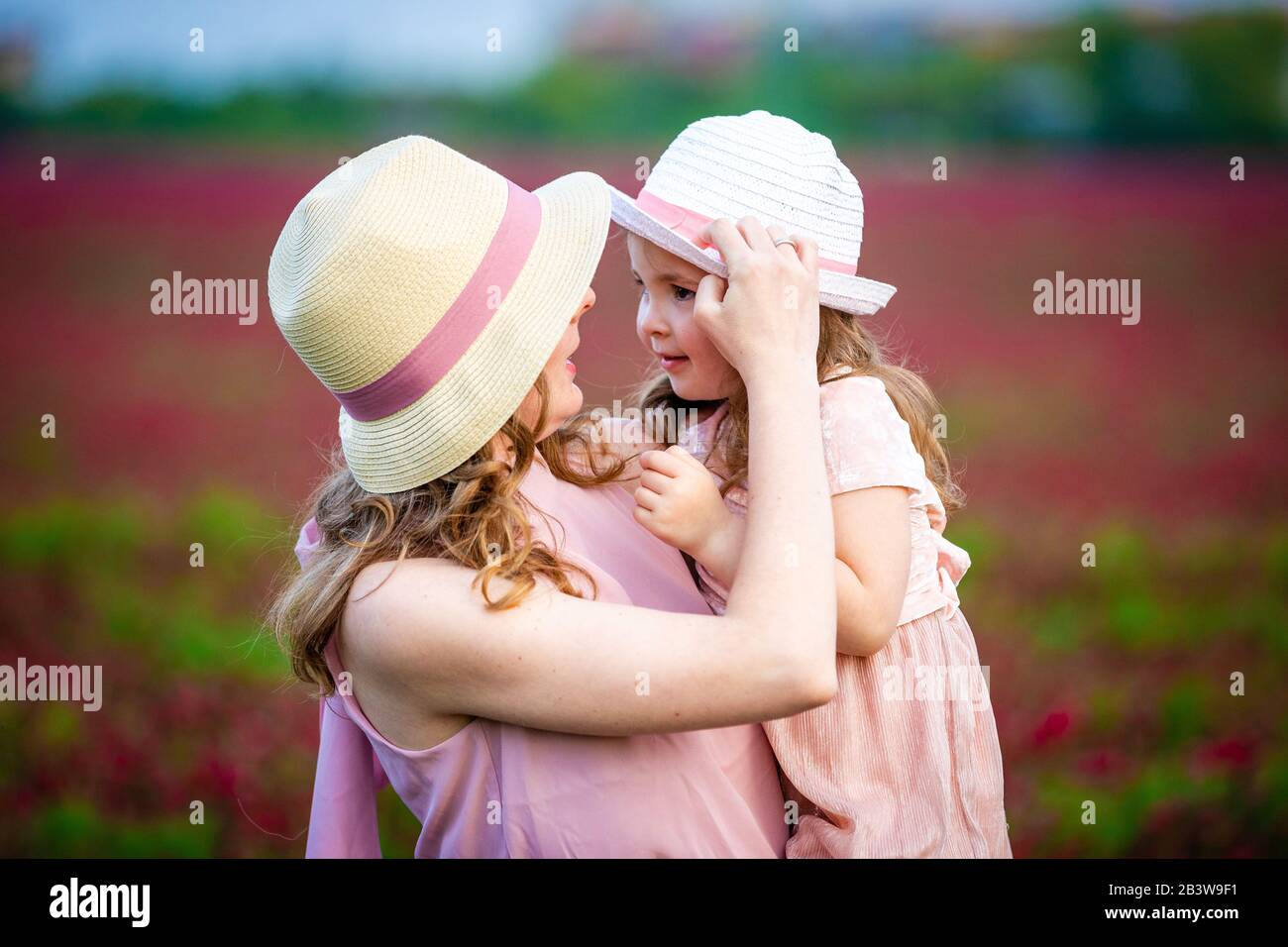 Beautiful smiling child girl with young mother in family look in field ...