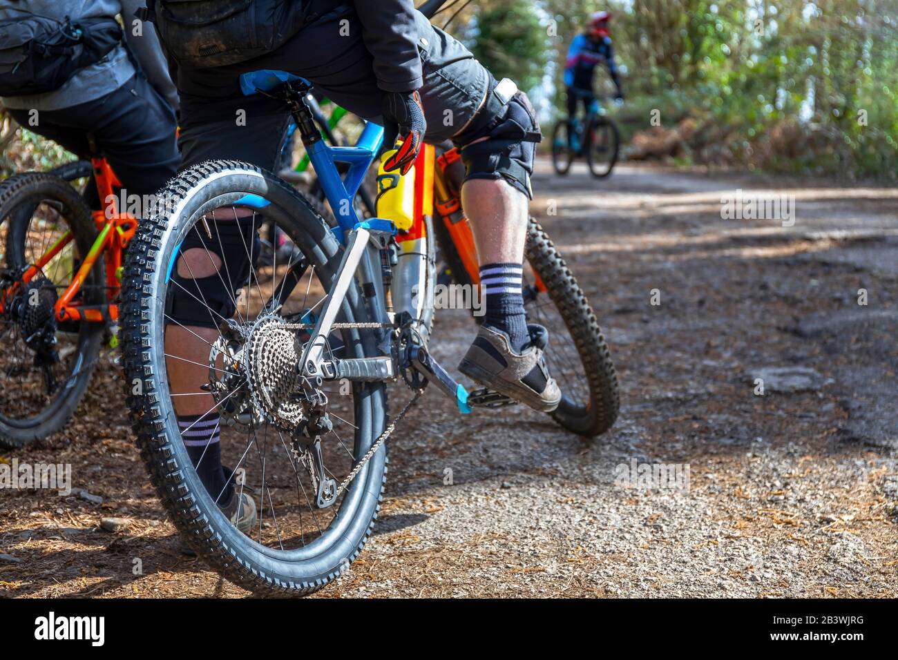 Two cyclists in the foreground, standing on their mountain bikes, await ...