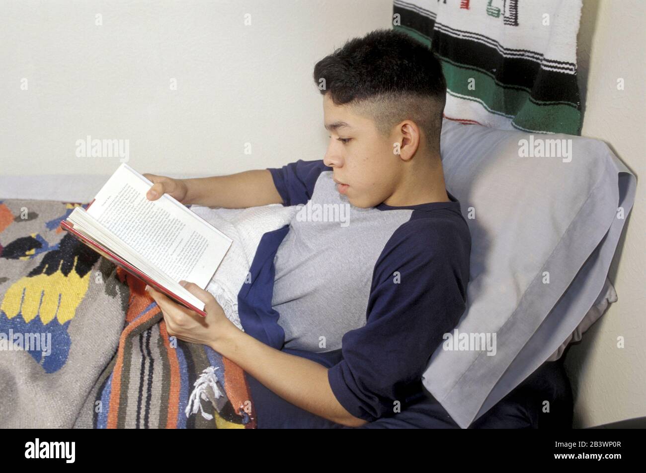 Austin, Texas: Hispanic teenage boy reading book in bed before falling ...