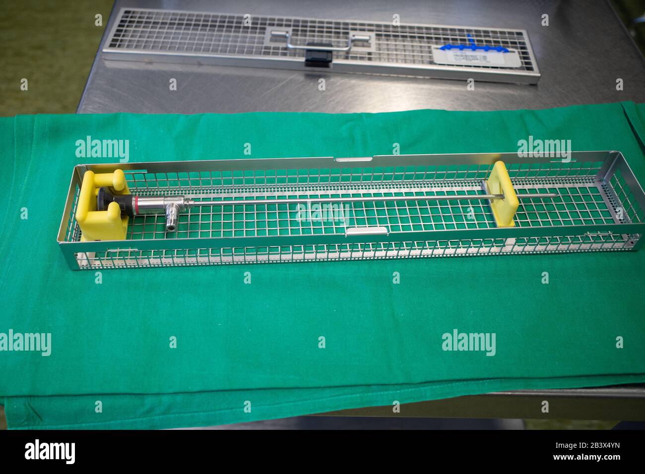 an endoscopic camera lies on a green surgical drape next to a tray ...