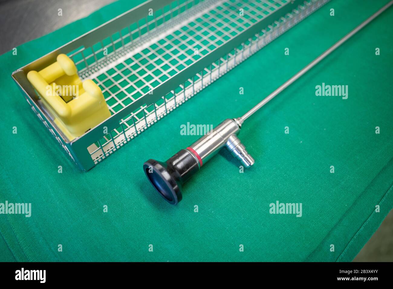 an endoscopic camera lies on a green surgical drape next to a tray ...