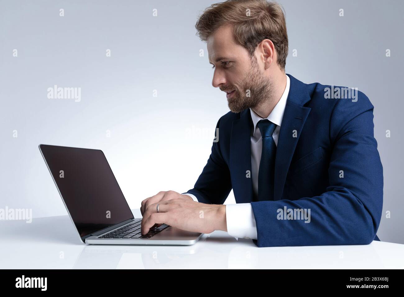 Side view of a handsome businessman working and writing on his laptop ...