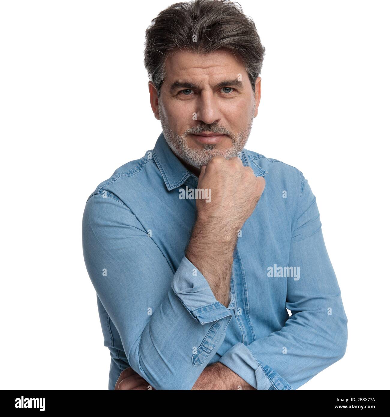 Determined casual man looking forward with his hand on his chin while ...