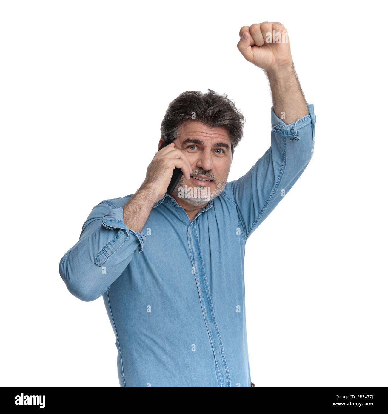 Happy casual man talking on his phone and celebrating with his fist in ...