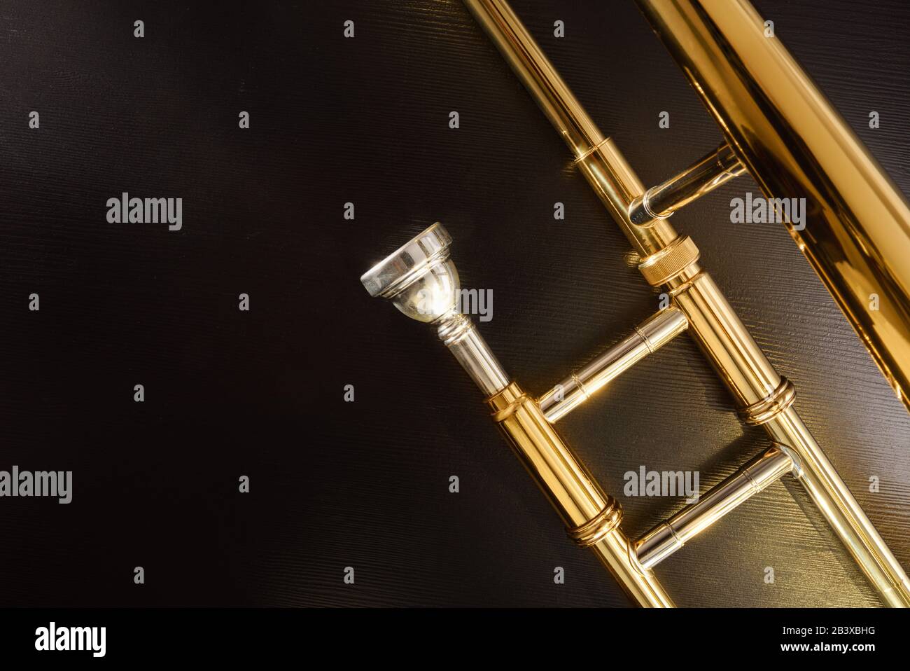 Detail of mouthpiece and trombone braces on black wooden table. Top ...