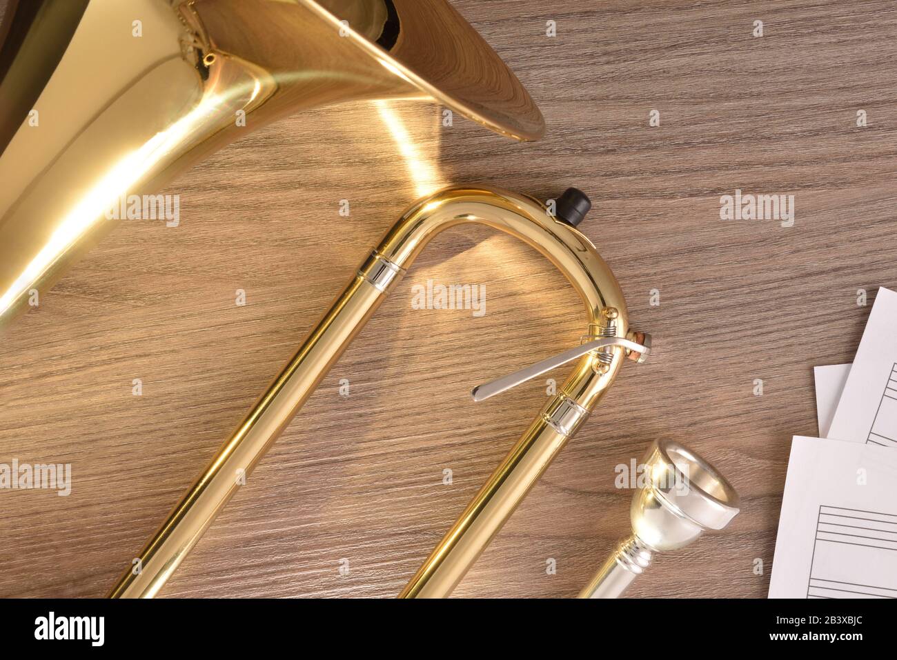 Golden slide trombone disassembled and scores on wooden table. Top view ...