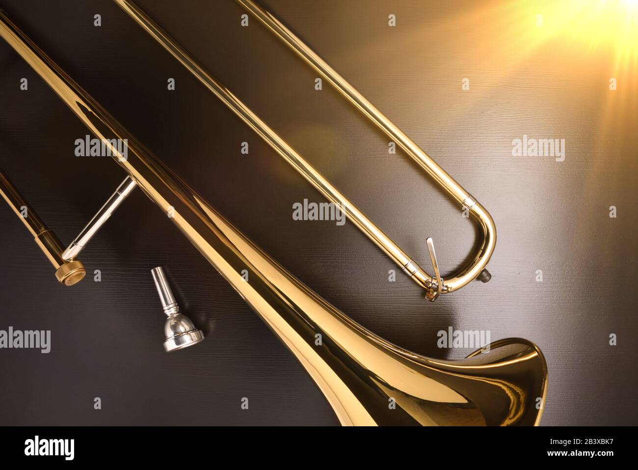 Golden slide trombone disassembled on black wooden table with yellow ...
