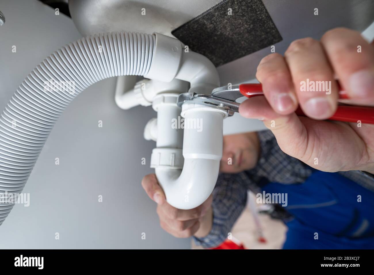 Young Plumber Working With Pipe Wrench In Kitchen Stock Photo - Alamy