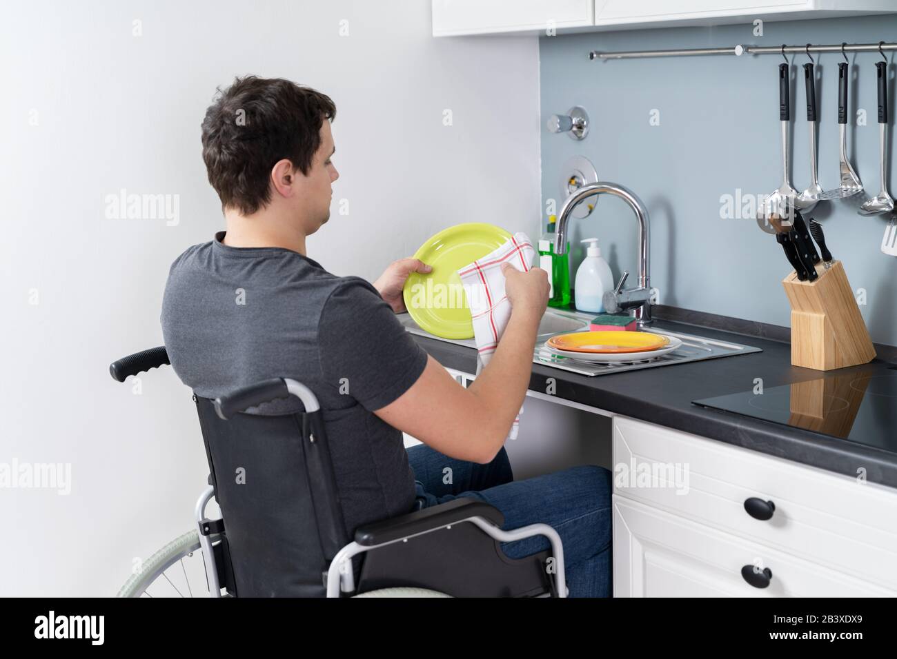Handicapped Man Sitting On Wheelchair Washing And Cleaning Dishes In ...