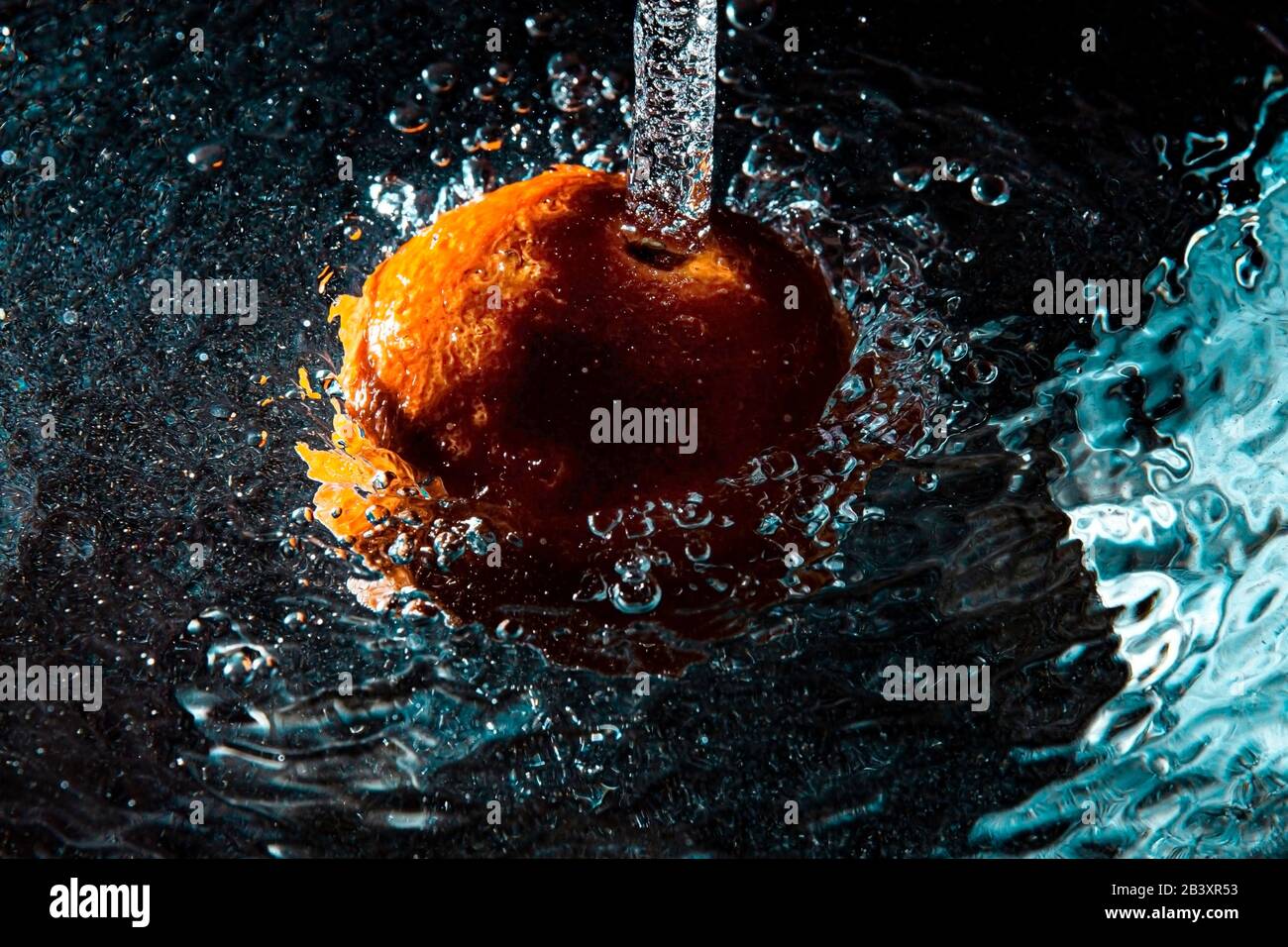 One fresh red orange under running water. Orange with drops of water ...