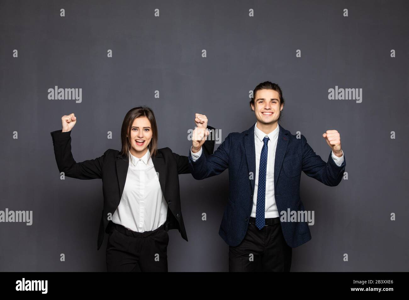 Young business woman and man showing winner gesture over gray ...