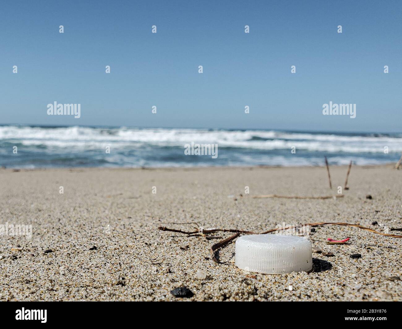 White plastic bottle cork on sandy sea coast, polluted ecosystem ...