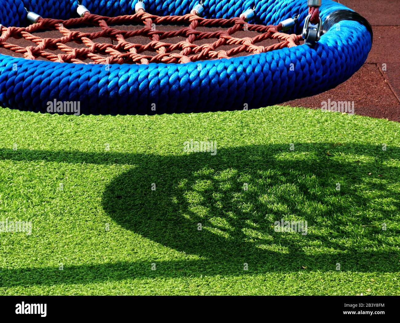 suspended circular vinyl playground swing detail with strong shadow on ...