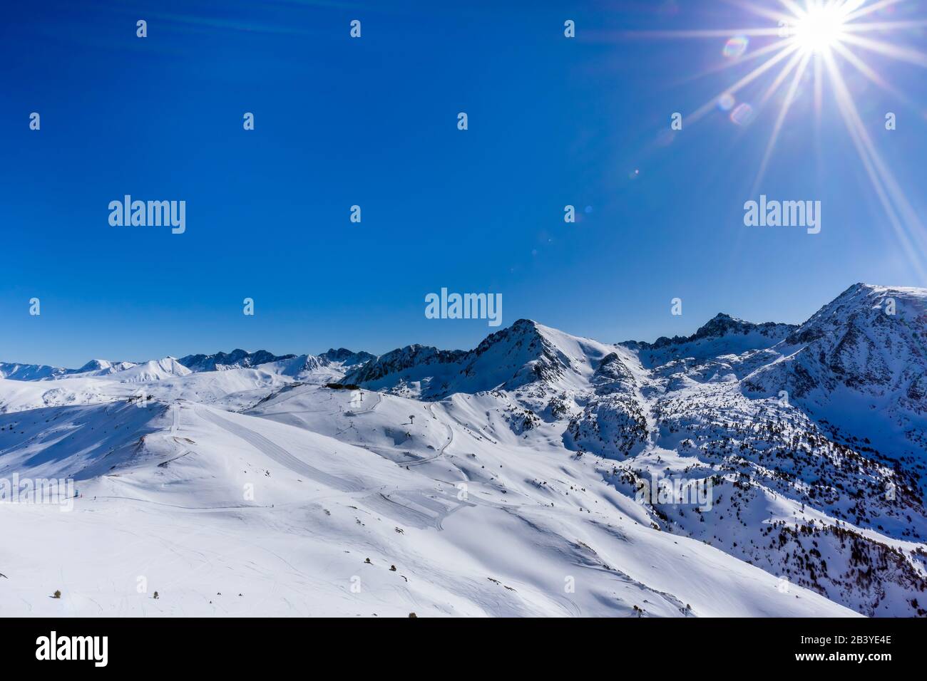Beautiful mountain range covered in snow with clear sky, lens flare and ...