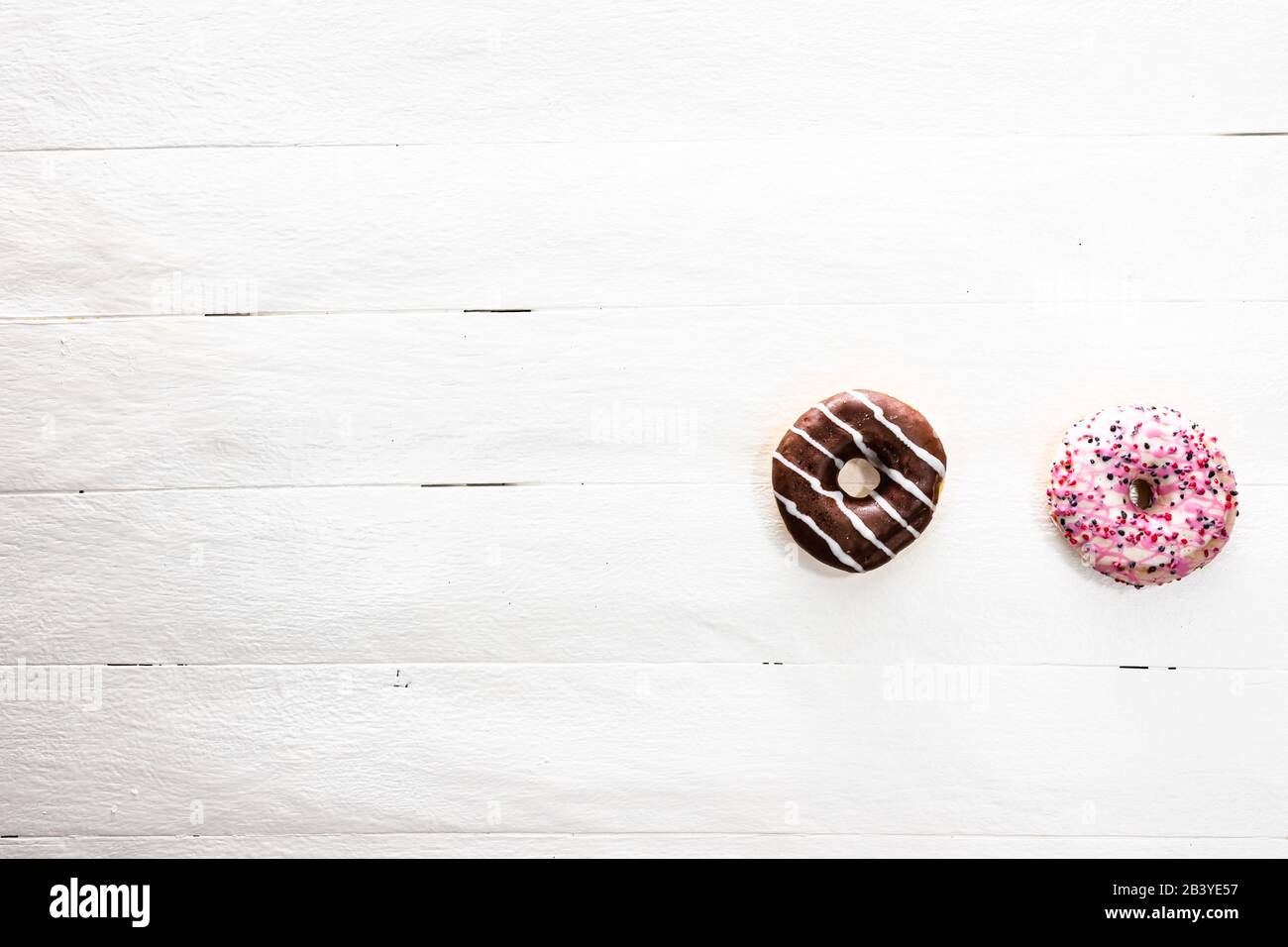 Colorful donuts on white wooden table. Sweet icing sugar food with ...