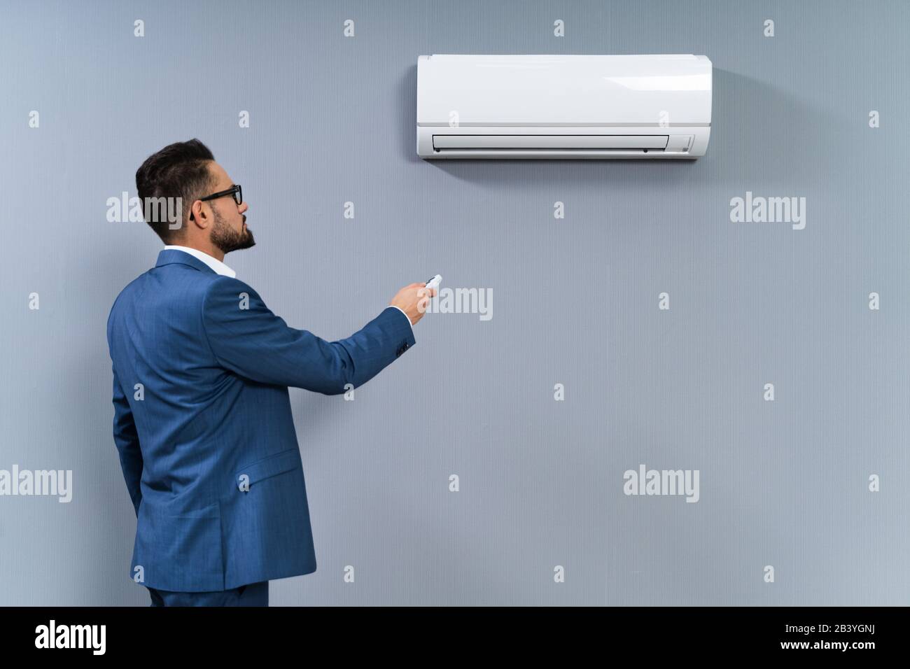 Portrait Of A Man Operating Air Conditioner With Remote Controller ...