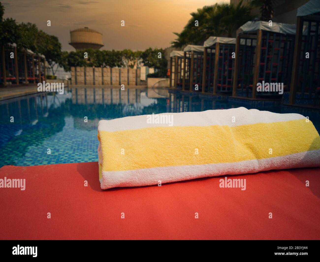 Yellow and white coloured towel on the poolside of a calm beautiful ...