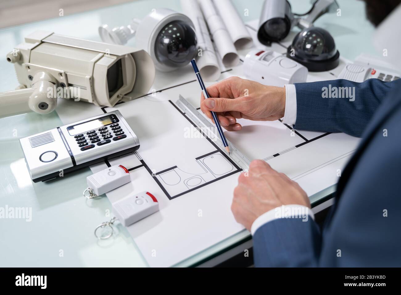 Architect Drawing Blueprint With Various Security Equipment On Desk ...