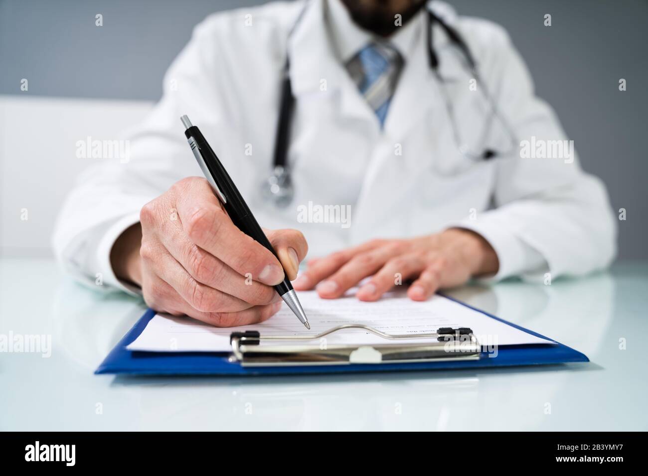 Doctor's Hand Signing Document On Desk In Clinic Stock Photo - Alamy