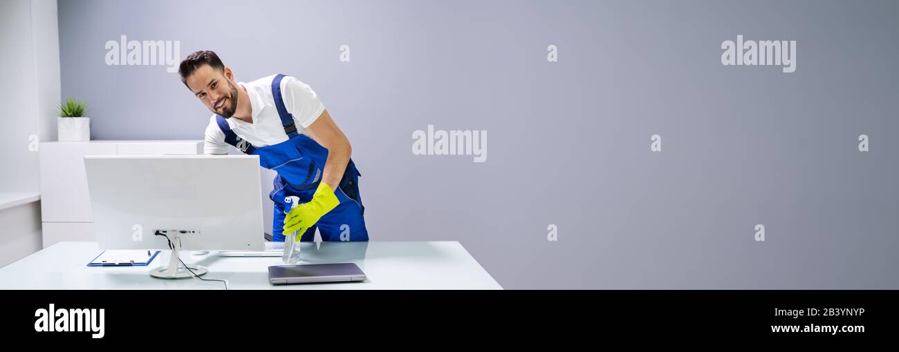 Worker Cleaning Computer Desk With Spray And Sponge Stock Photo - Alamy