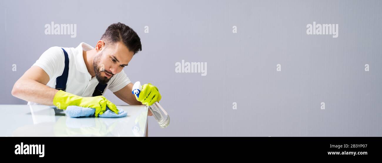 Worker Cleaning Computer Desk With Spray And Sponge Stock Photo - Alamy