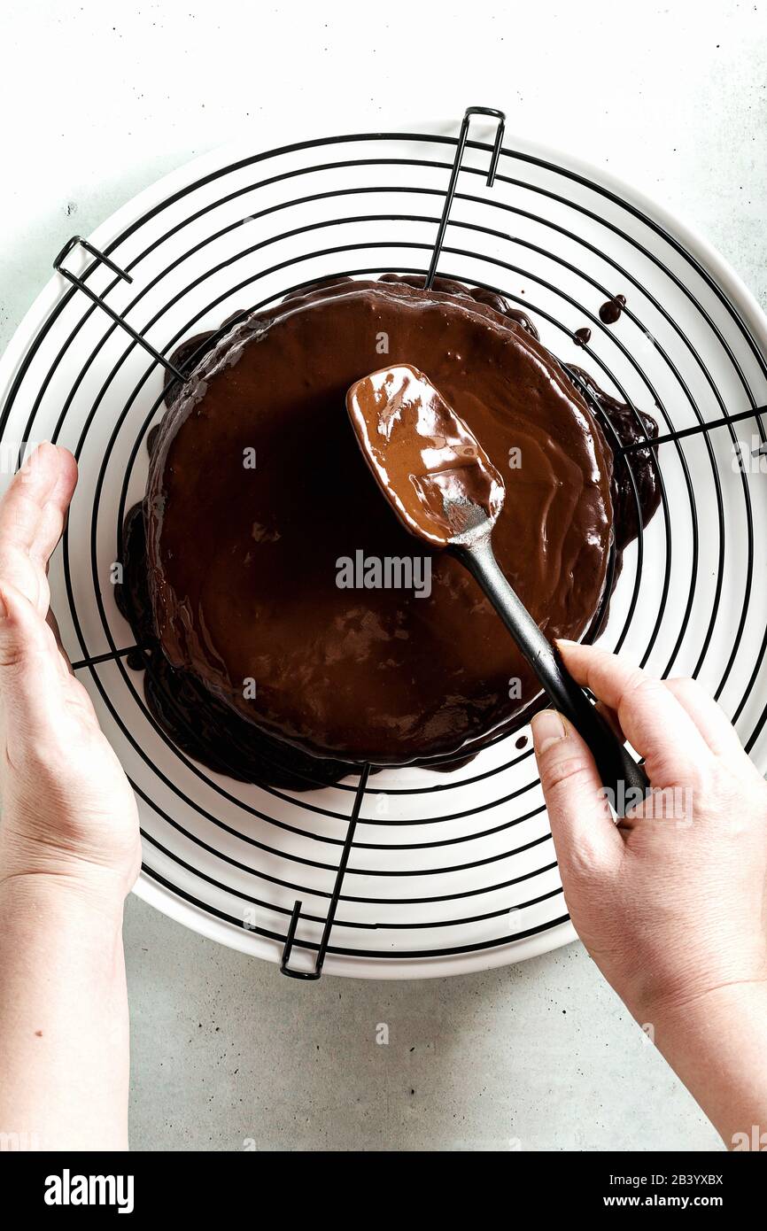 pouring chocolate ganache on the cake. female hands Stock Photo - Alamy