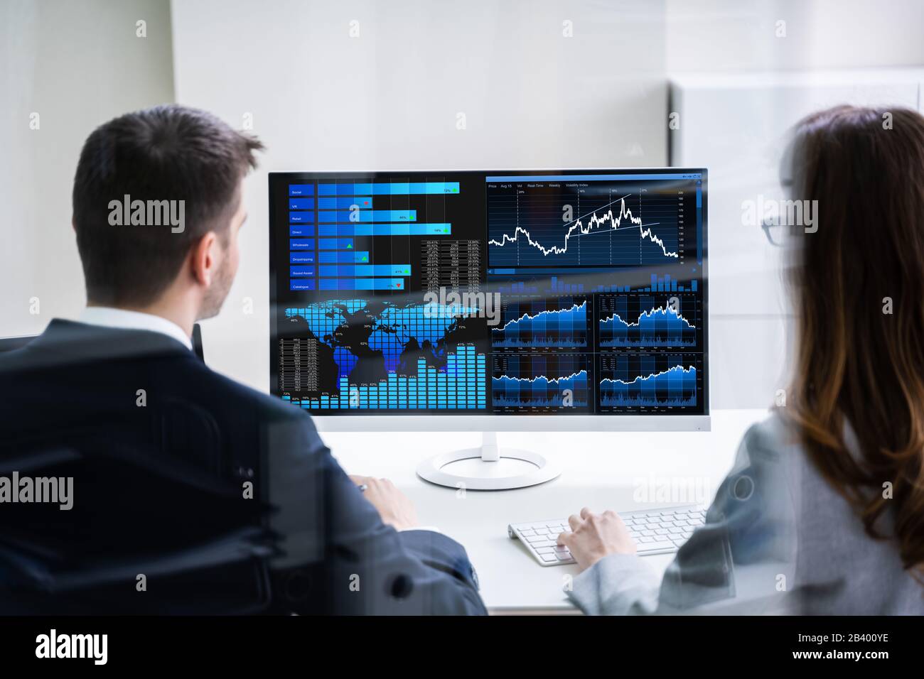 Two Businesspeople Examining Graph On Computer At Workplace Stock Photo ...