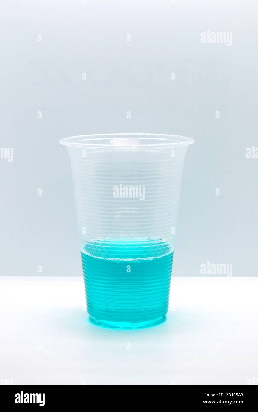 Plastic cup with bright turkish blue color liquid on a white background ...