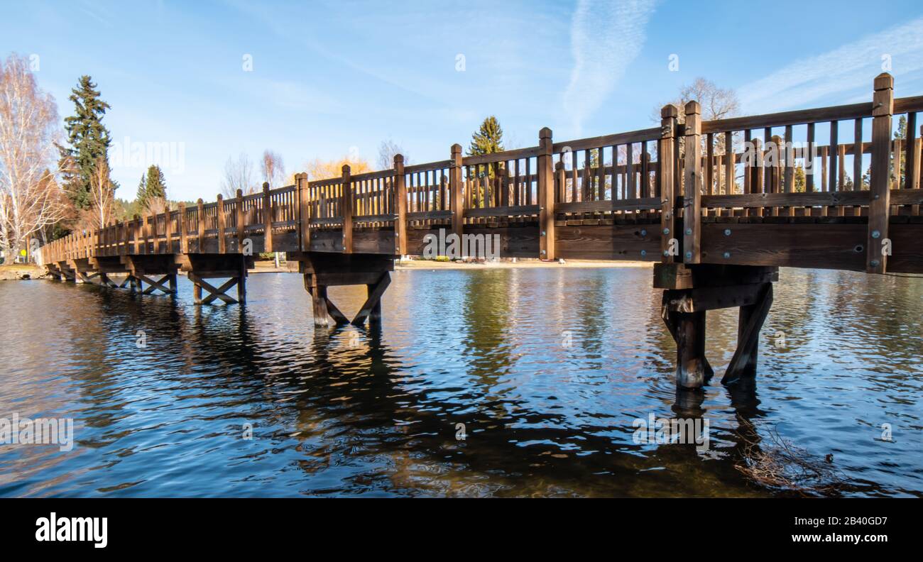 Long wood foot and bike bridge over river in a downtown park Stock ...