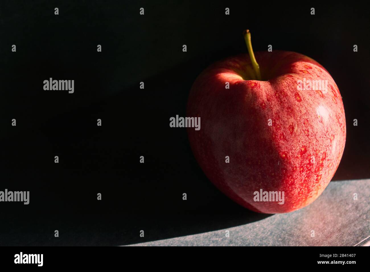 red apple with natural window light, creating shadow and black ...