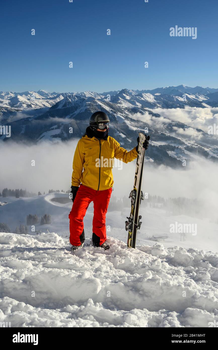 Skier standing at the ski slope holding ski, view into the distance ...