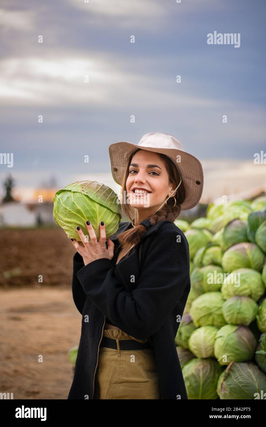 Farm girl with a cabbage in her hands in front of a truck full of ...