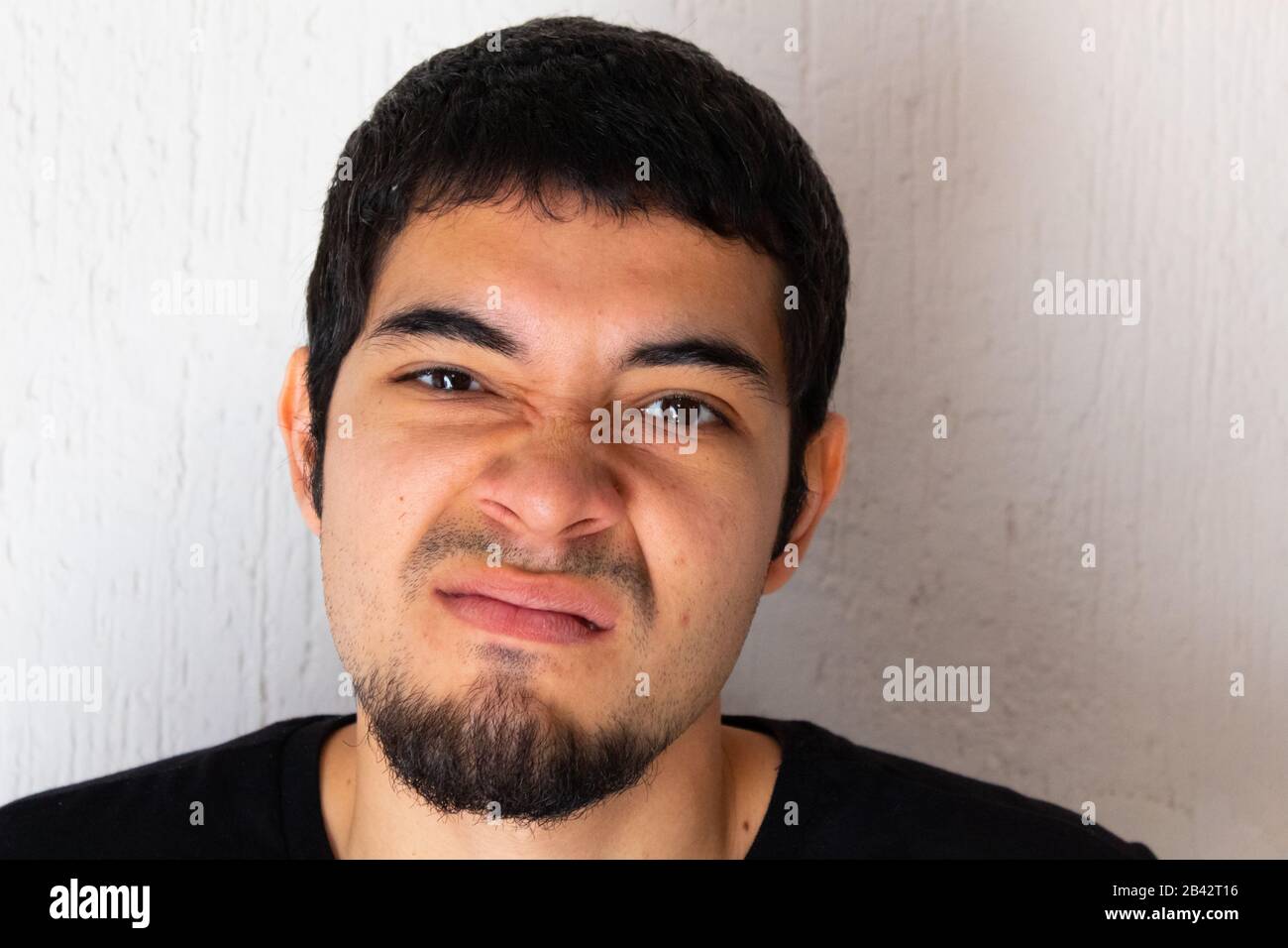 Young short-haired Hispanic man with black clothes, angry, furious ...