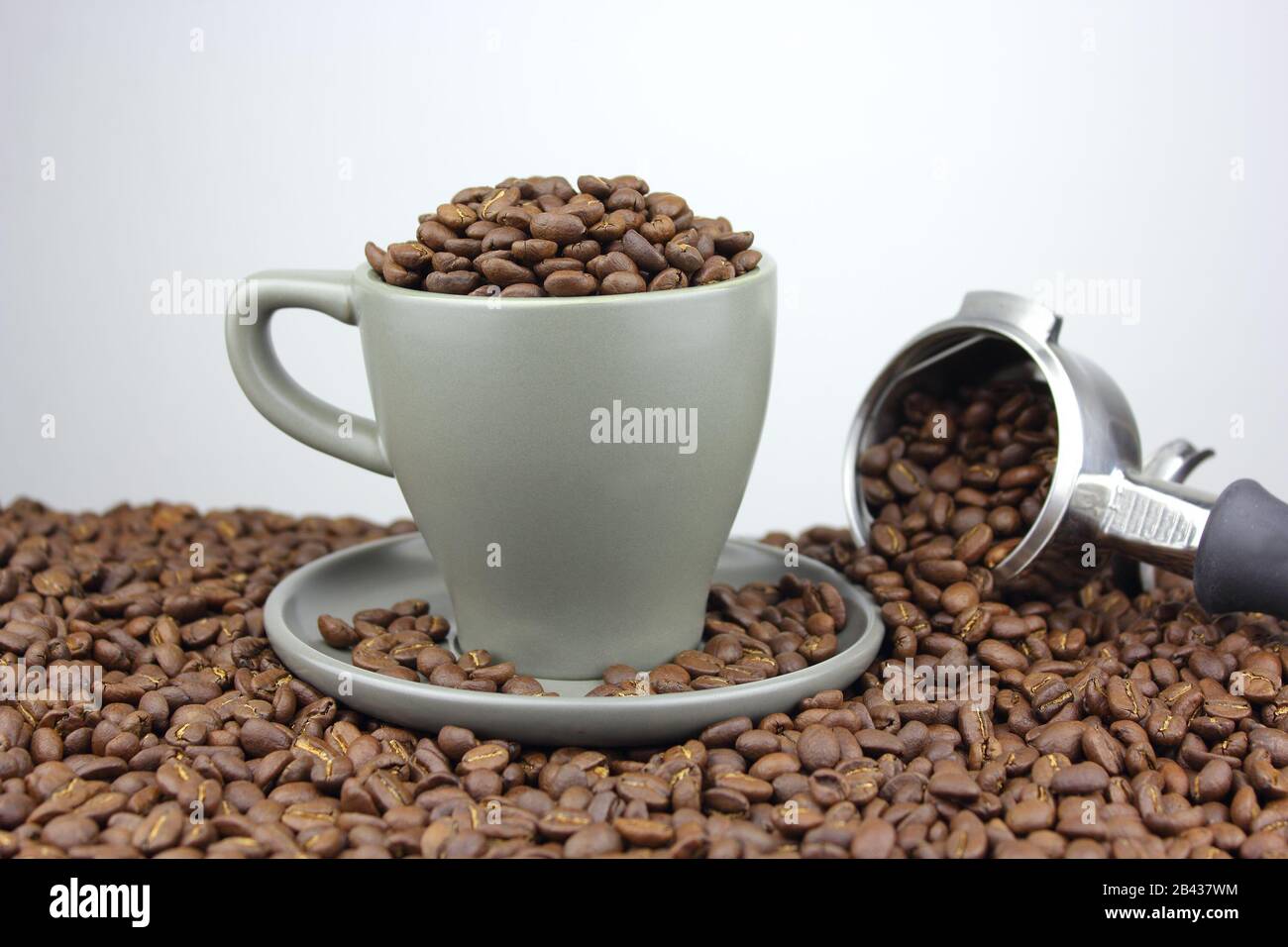 Dark roasted coffee beans in a cup and saucer with a group handle Stock ...