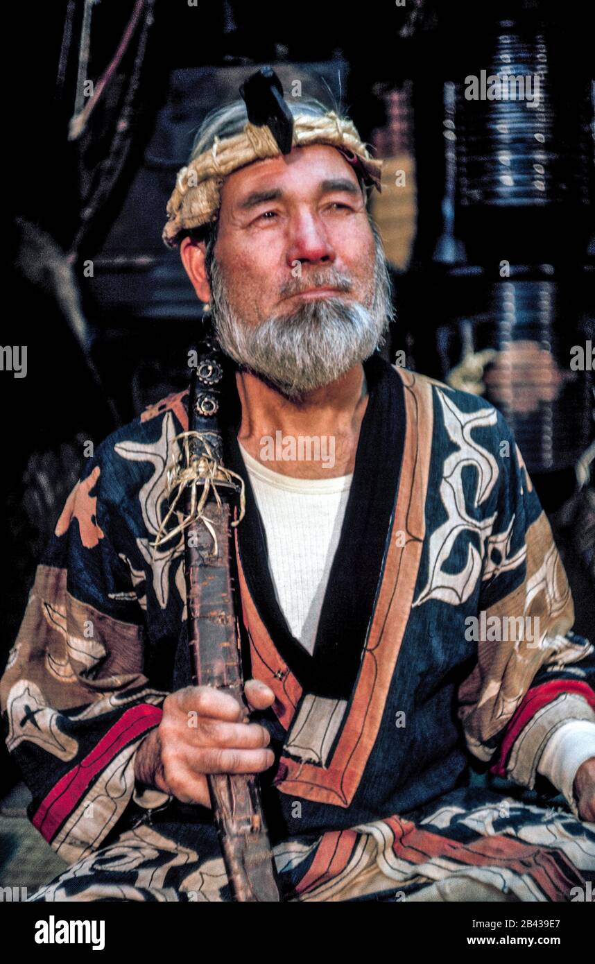 A 70-year-old bearded Ainu man in traditional dress and wearing a crown ...