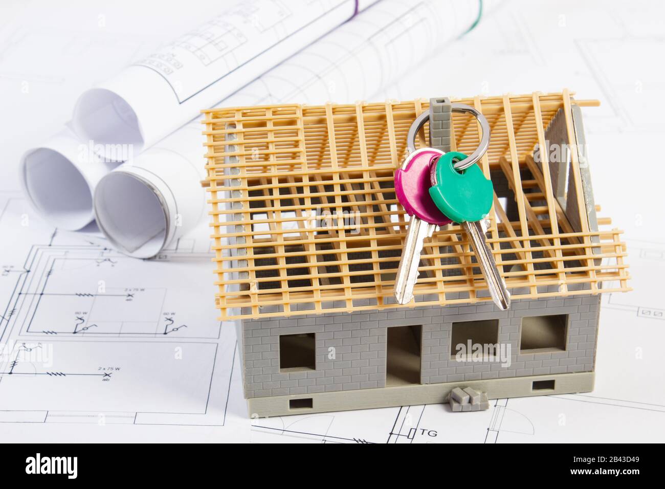 Small house under construction with home keys and electrical rolls of ...