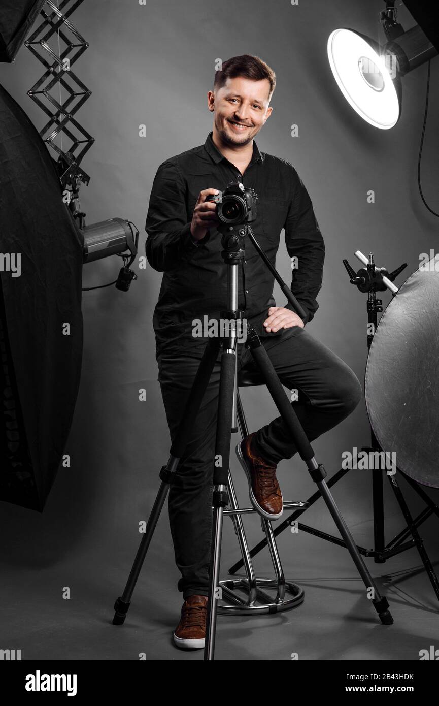 Happy man photographer with camera on a studio equipment background ...