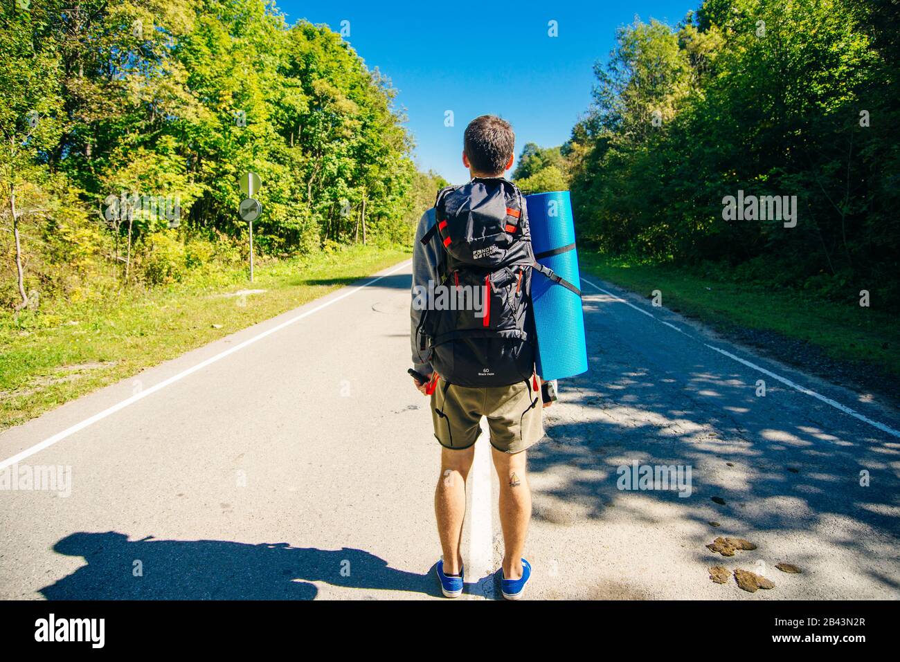 Young tourist with a large backpack walks on an asphalt road Stock ...