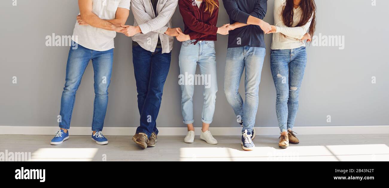A group of people hold each other's hands while standing against the ...