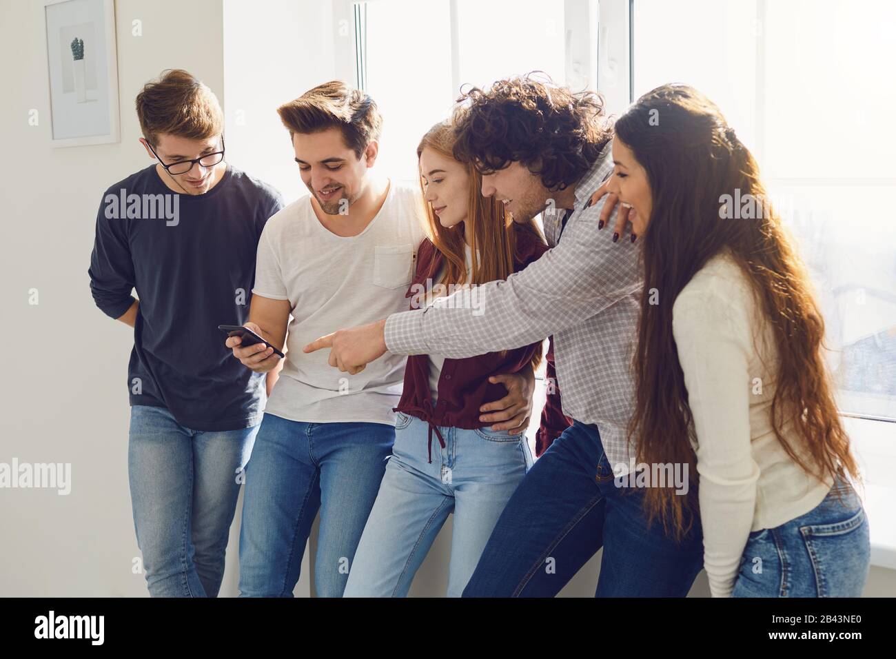Group of happy friends looking at the phone laughing smiling in a ...