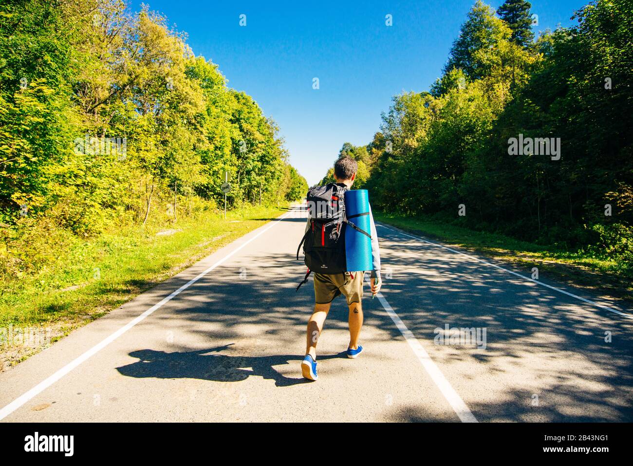 Young tourist with a large backpack walks on an asphalt road Stock ...