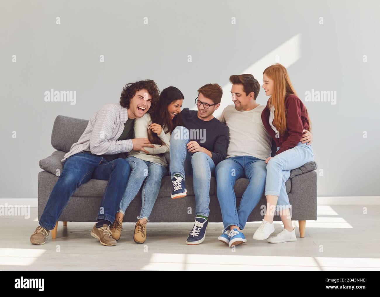 A group of friends is sitting on couch in a room on a gray background ...