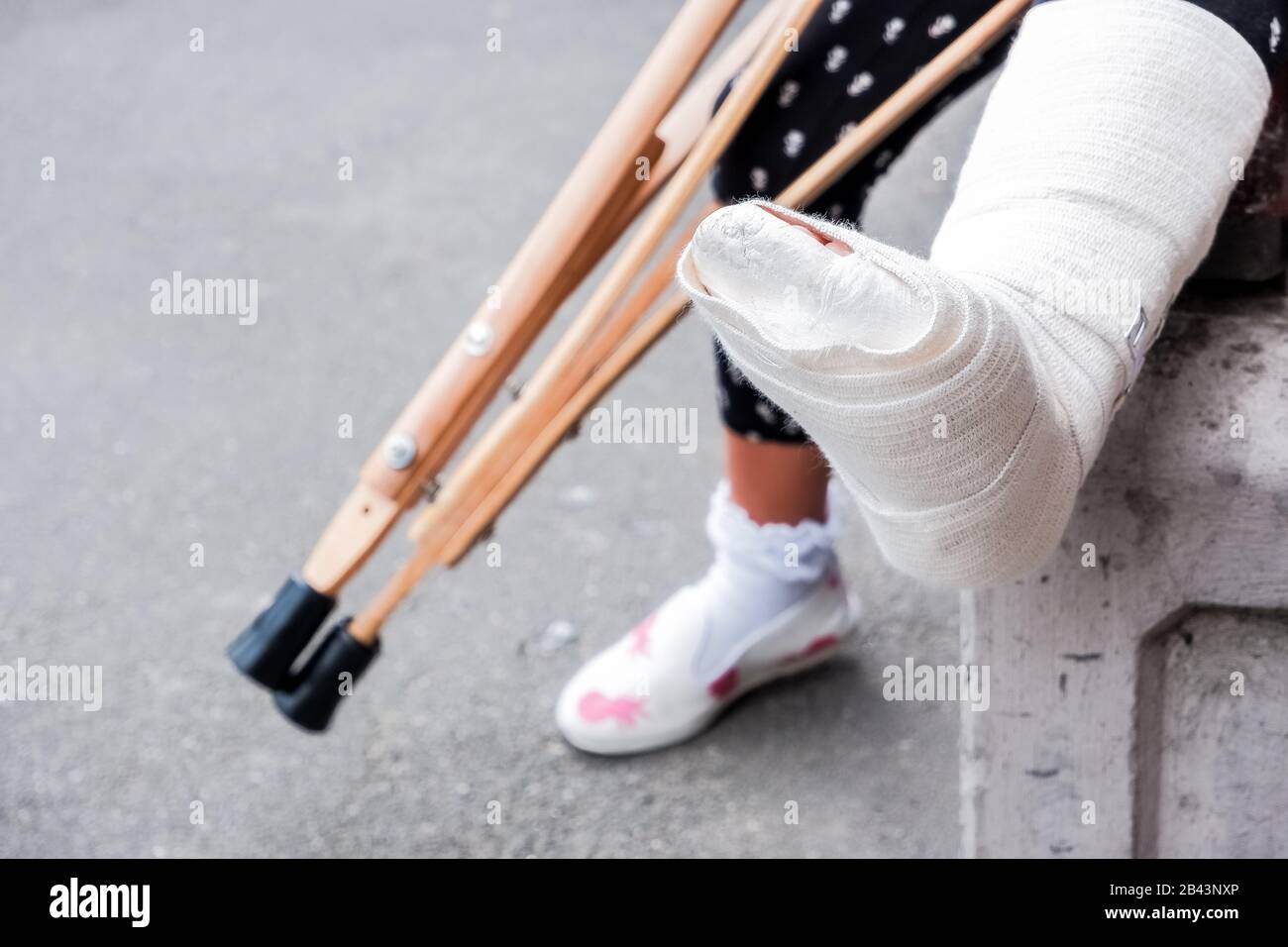 unrecognizable girl sits on the street on a bench with a broken leg and ...