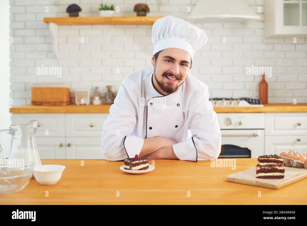 Confectioner man smiles while standing with cake in his hands at the ...