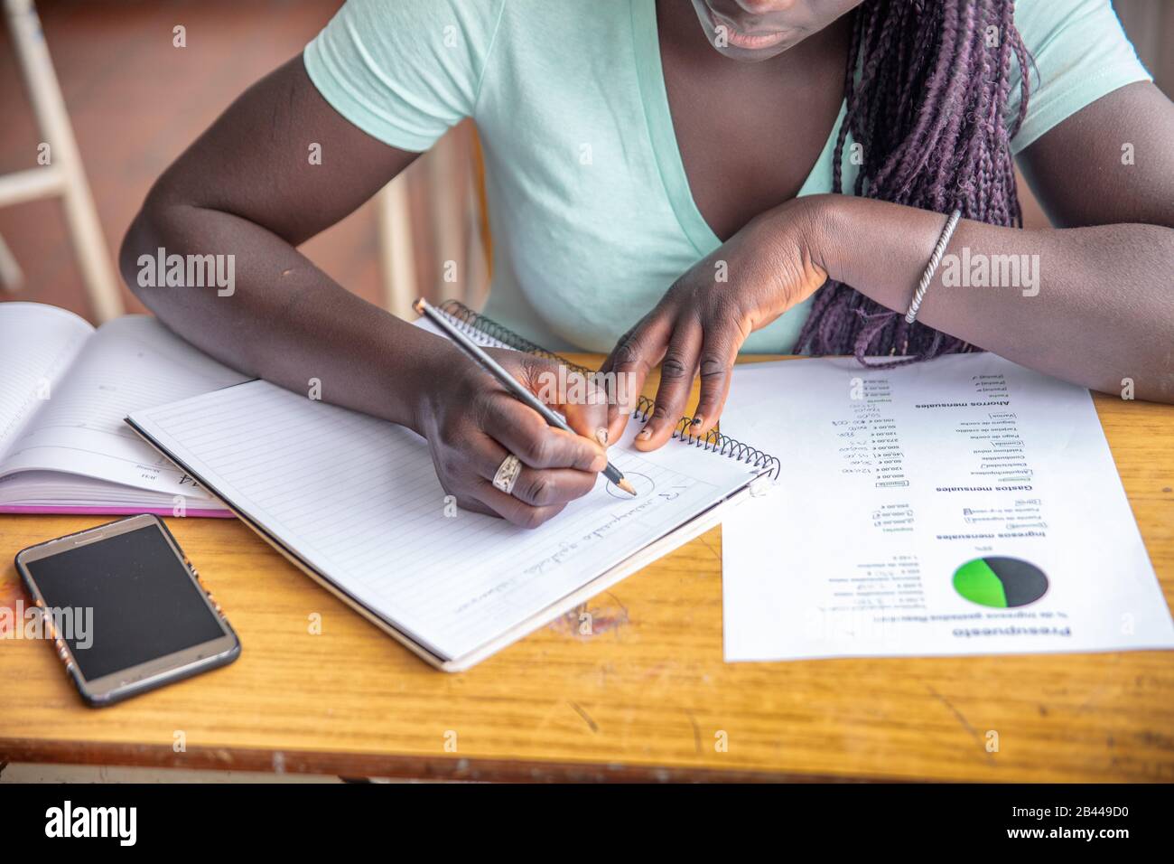 African teenager writing on textbook at school desk Stock Photo - Alamy