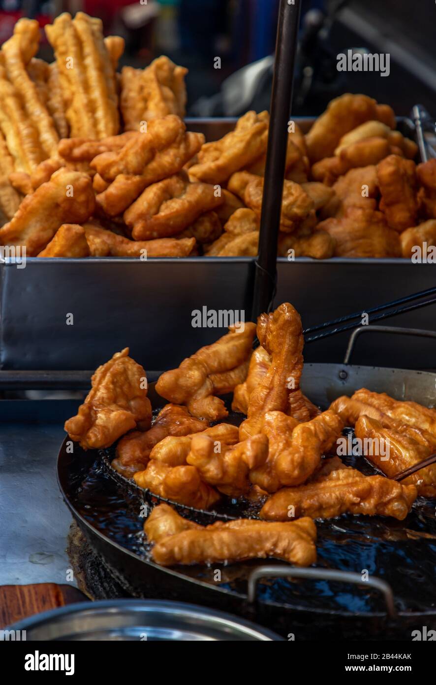 Chinese deep fried dough in hot oil on steel pan. Youtiao, Padnoongo or ...