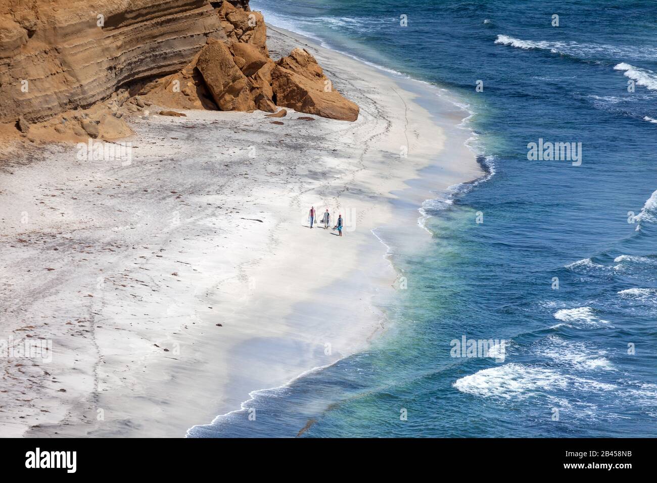 Three people walk along the ocean coast, Paracas, National Park, Peru ...