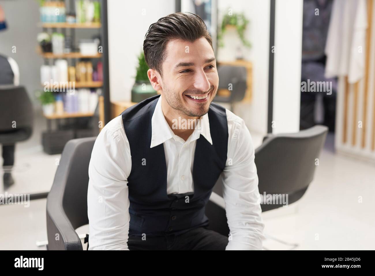 Smiling barber sitting in hair salon Stock Photo - Alamy